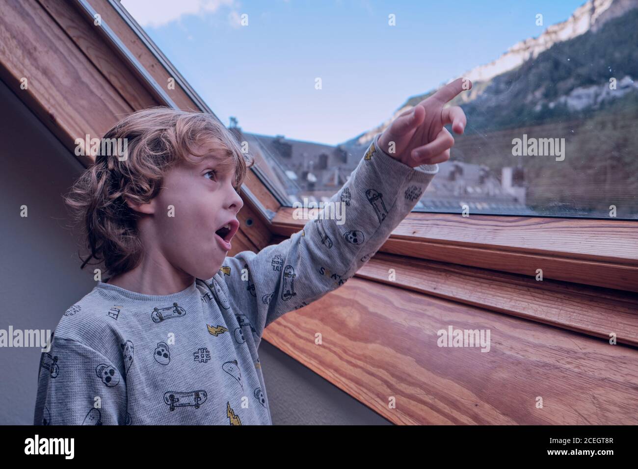 Cute little boy in pajamas pointing at wonderful mountain while looking ...
