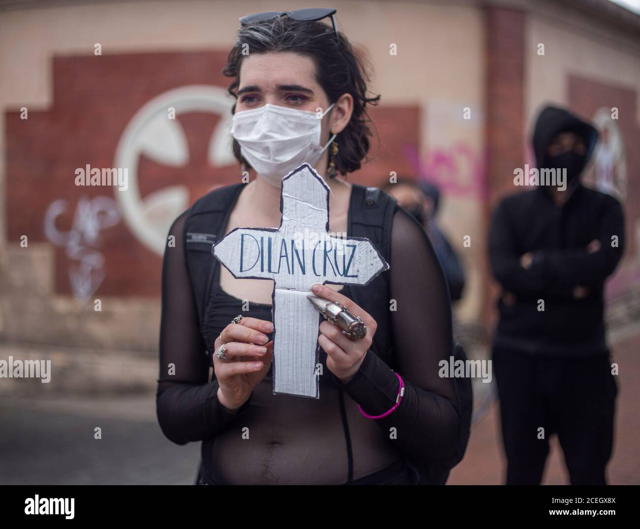 A woman marches holding a cardboard cross with the name of "Dilan Cruz ...
