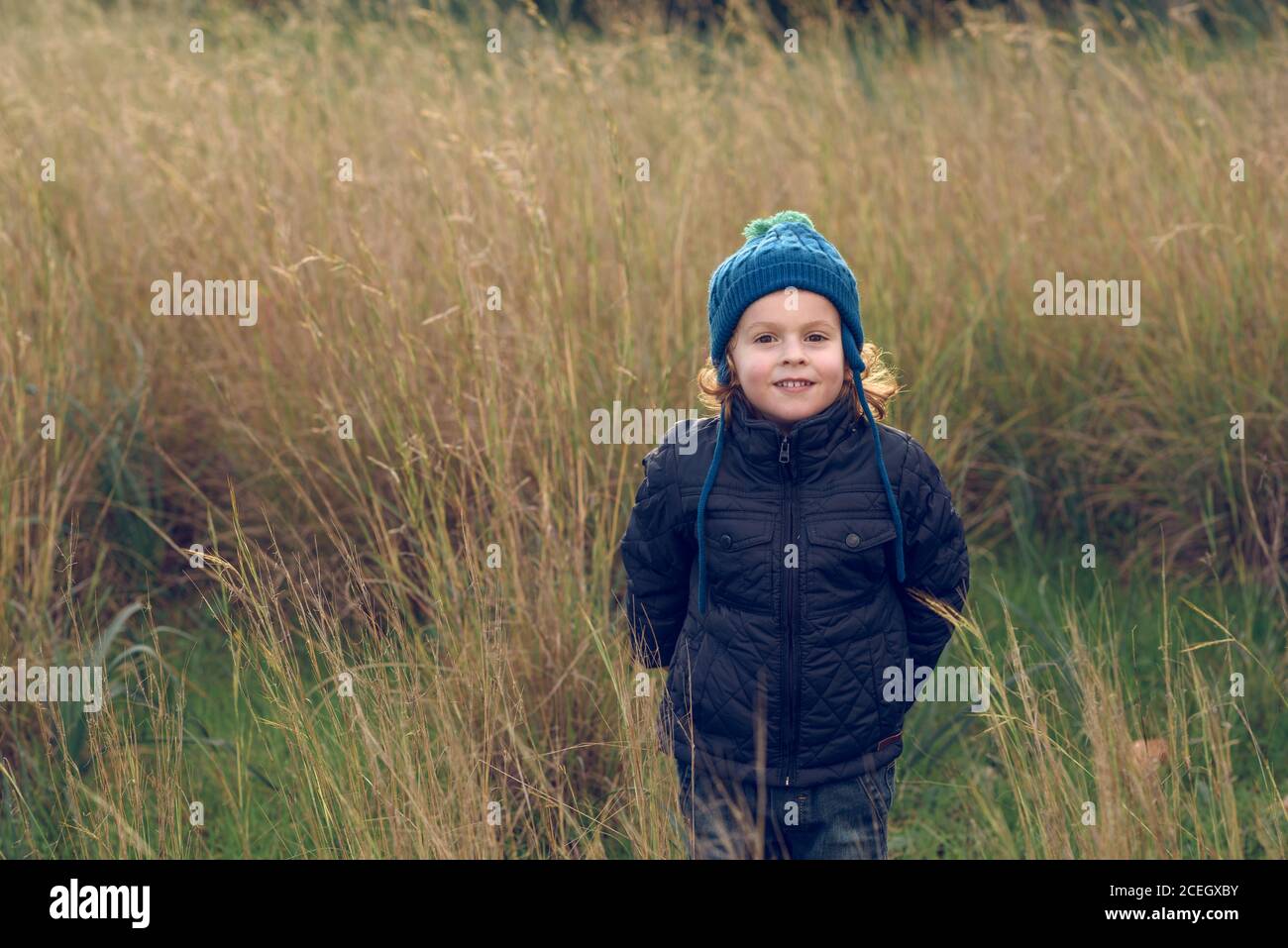 Cheerful little boy standing in grass Stock Photo - Alamy