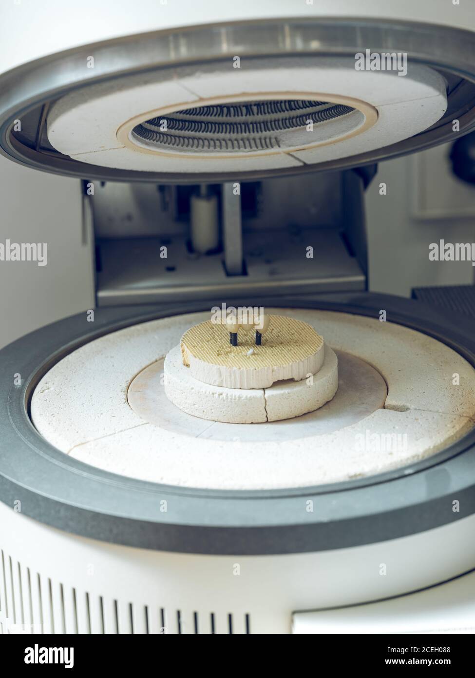 Three ceramic teeth standing inside modern tooth making machine in lab ...