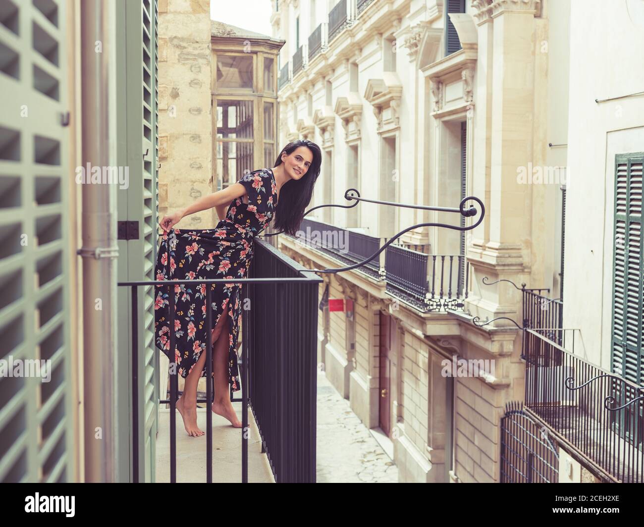 Beautiful young Woman standing on balcony in city Stock Photo - Alamy