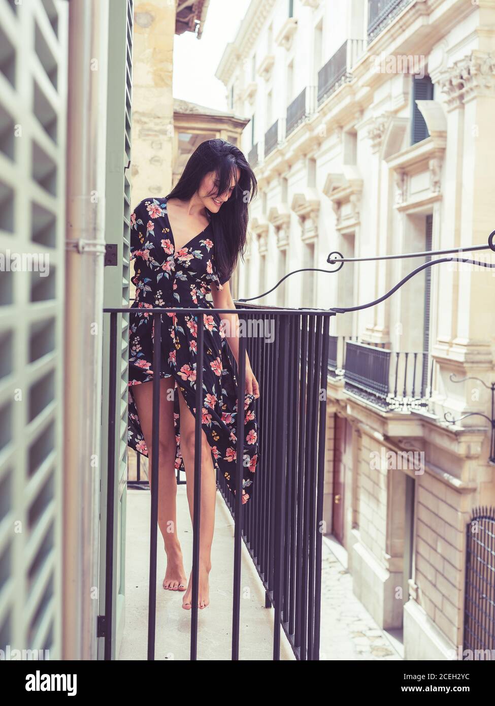 Beautiful young Woman standing on balcony in city Stock Photo - Alamy
