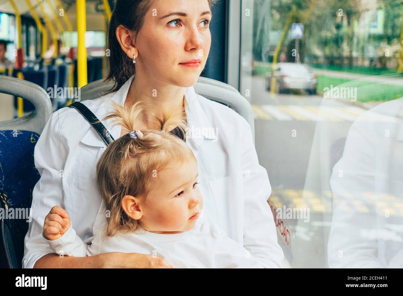 Caucasian toddler looking out the window of public bus with mom Stock ...