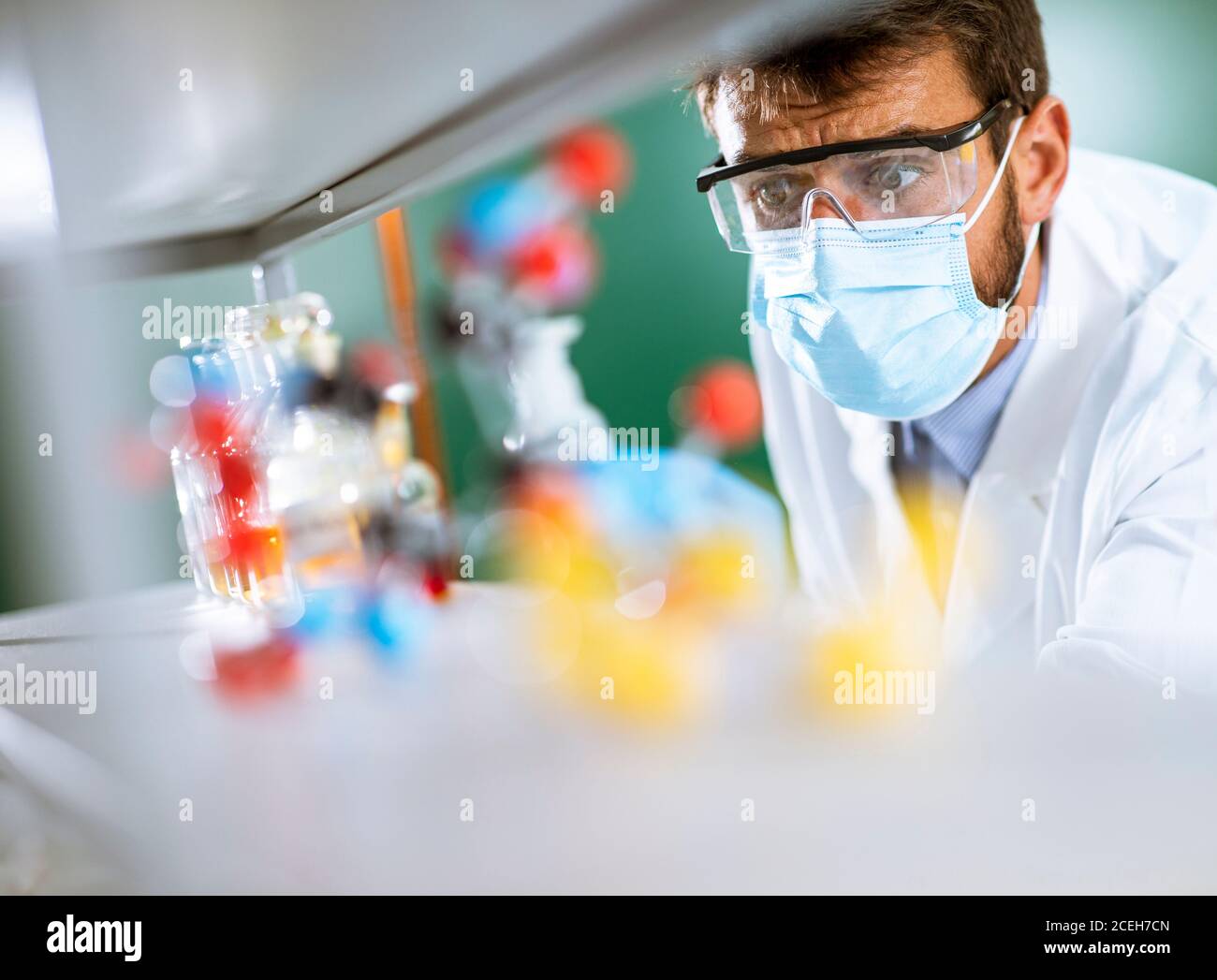 Young researcher with protective goggles checking test tubes in the ...