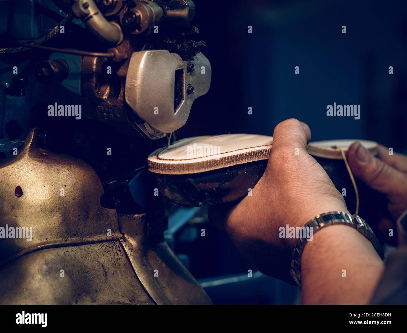 Hands of unrecognizable shoemaker using industrial sewing machine to ...