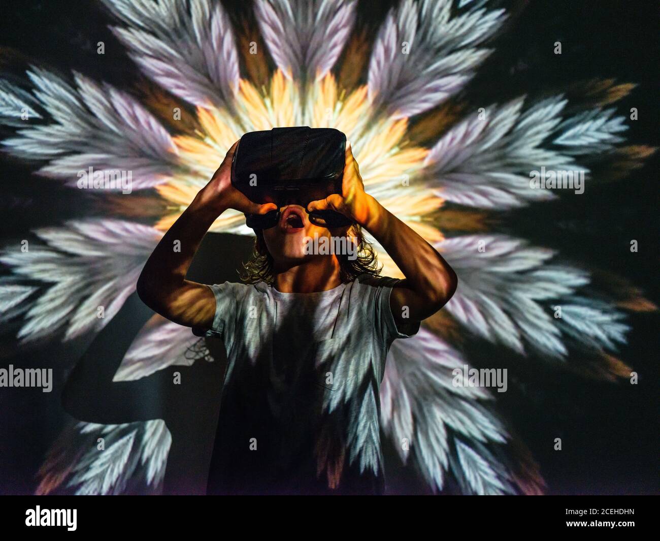 Bright projection on excited boy in VR headset Stock Photo - Alamy