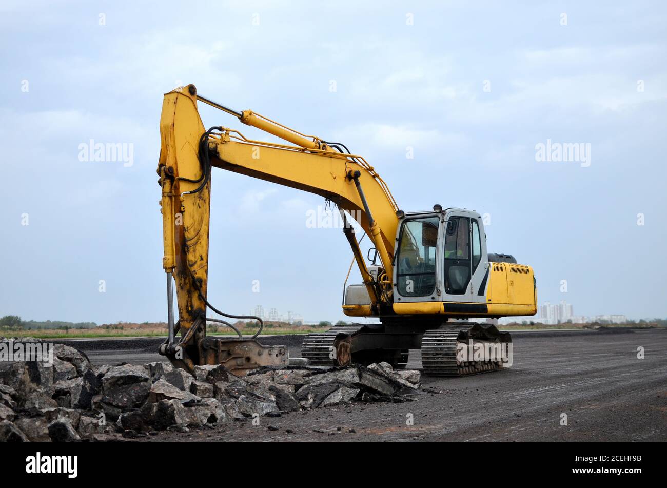 Large tracked excavator with hydraulic hammer breaks asphalt at a ...