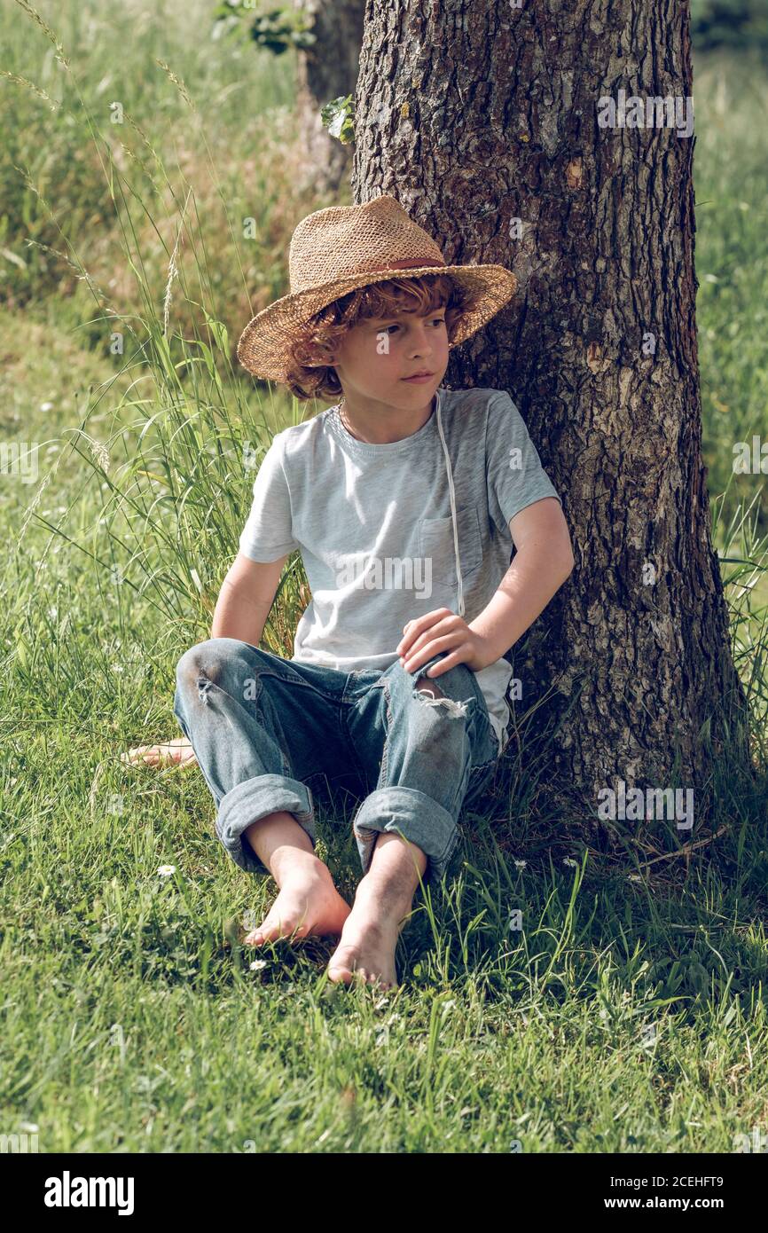 Boy sitting under tree in hi-res stock photography and images - Alamy