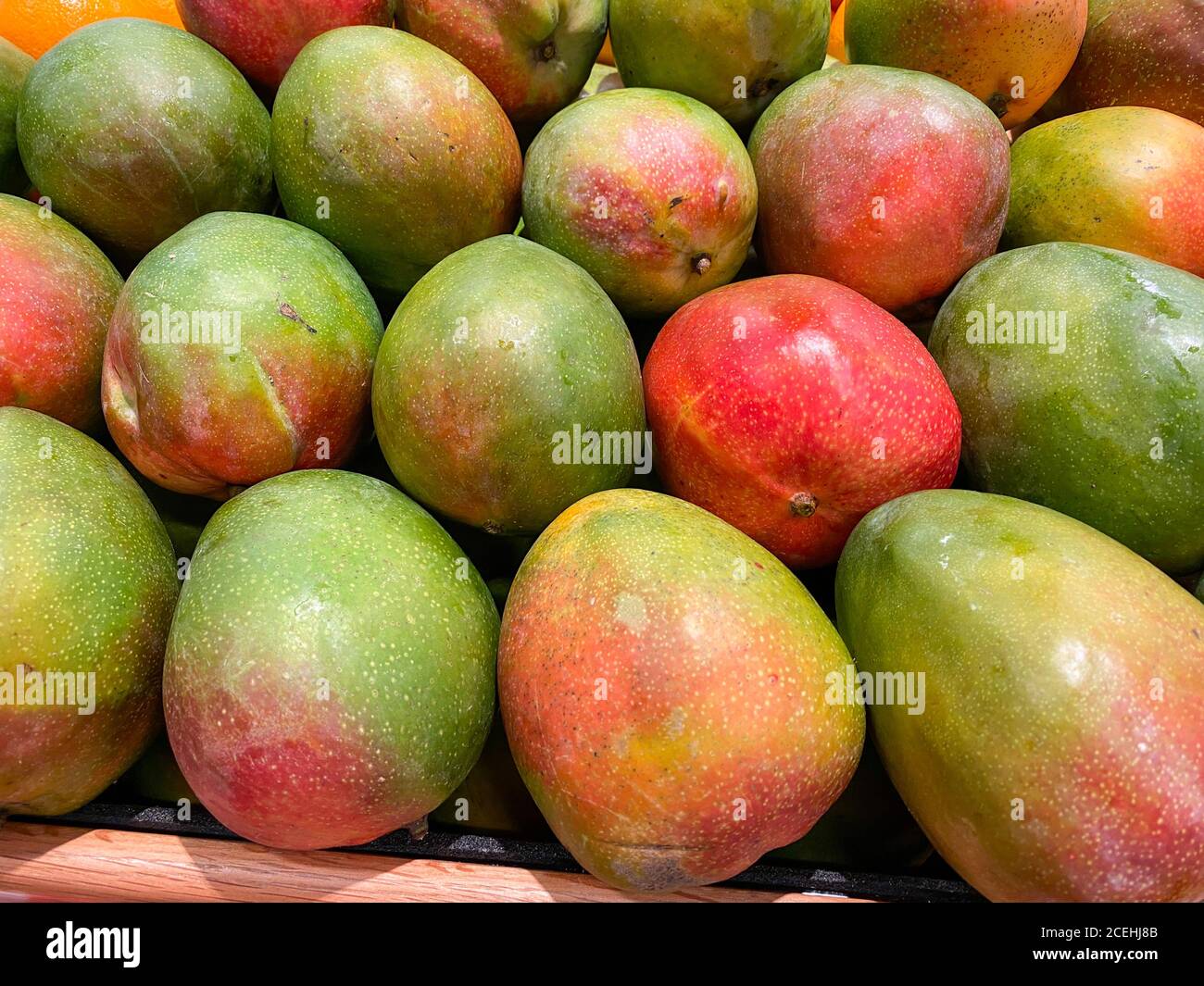 Ripe colorful mangos in a bin at a grocery store Stock Photo - Alamy