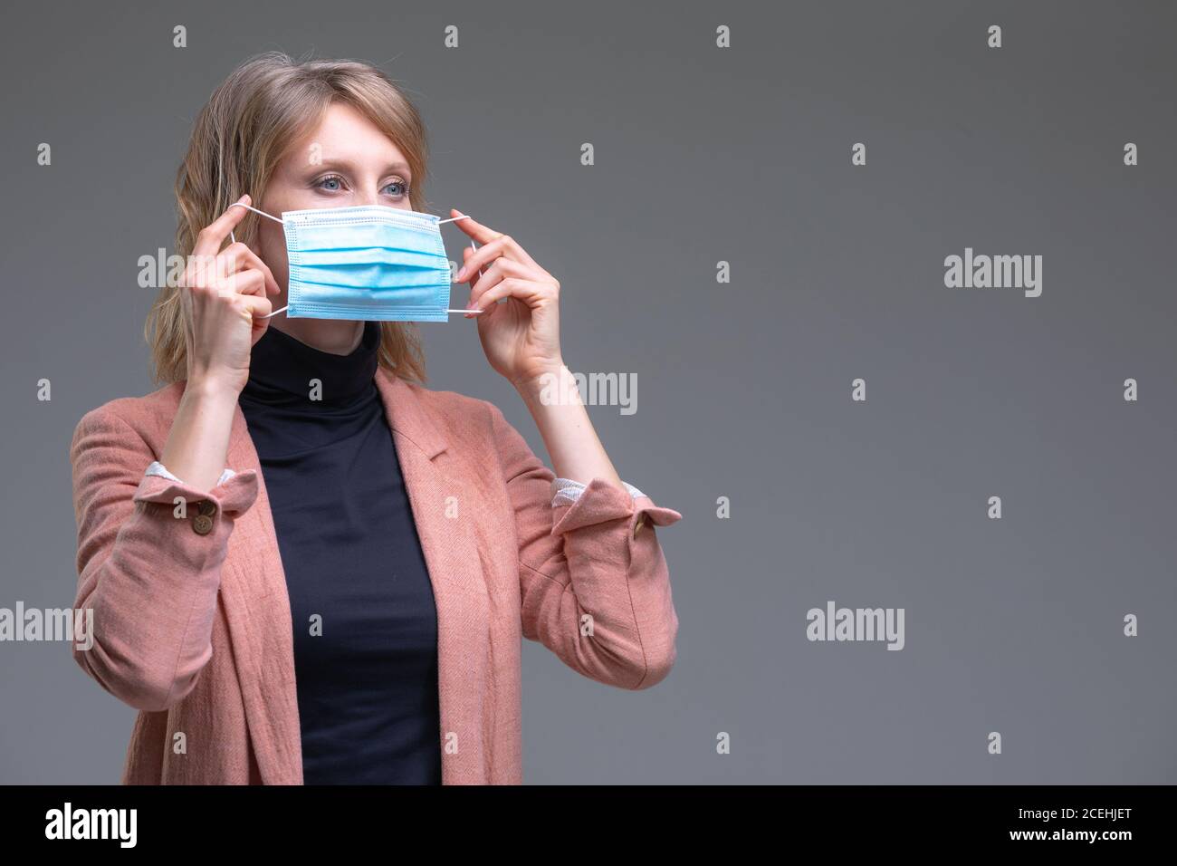 Blond woman hold her surgical mask Stock Photo - Alamy