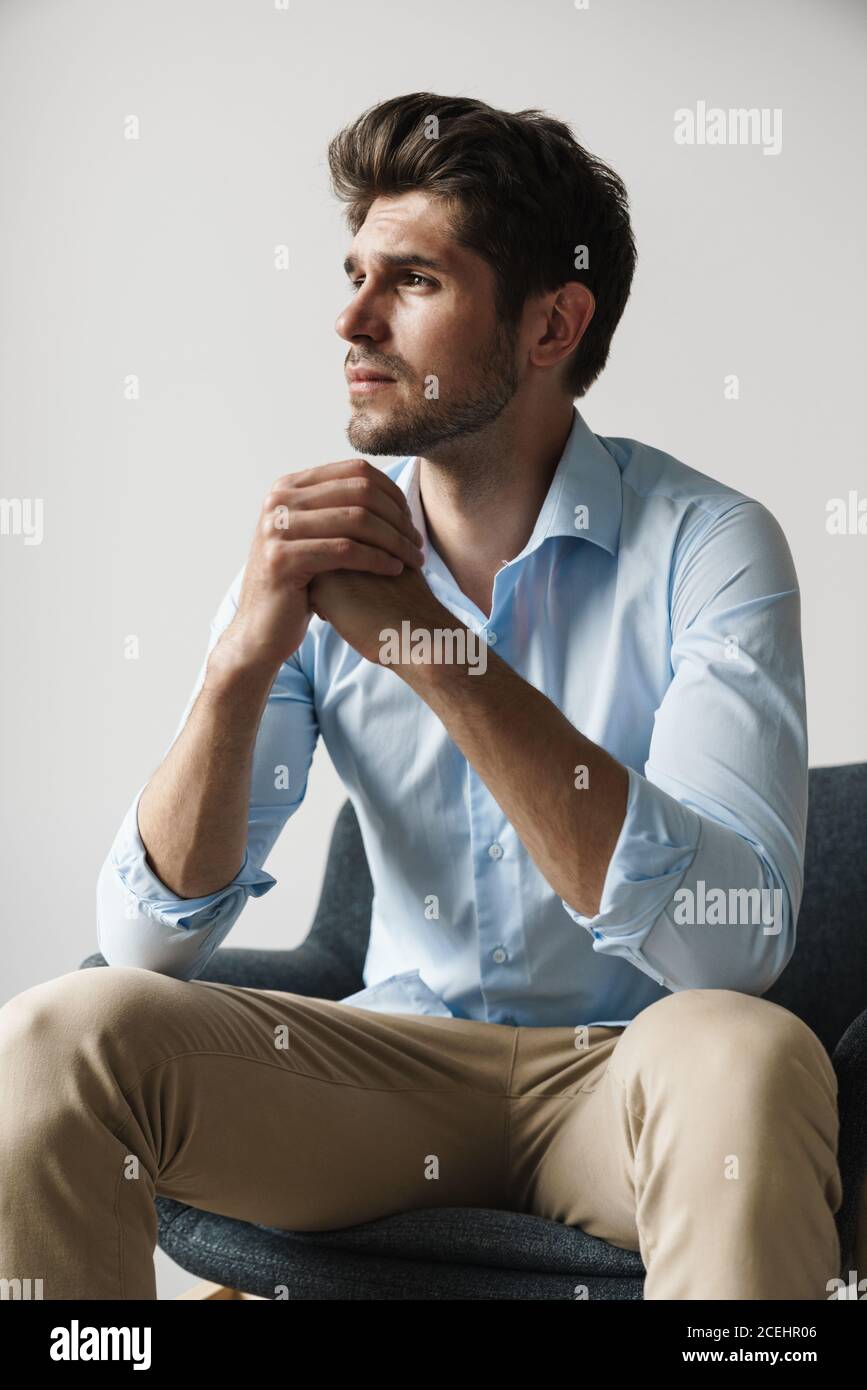 Image of serious businesslike brunette man thinking and sitting on ...