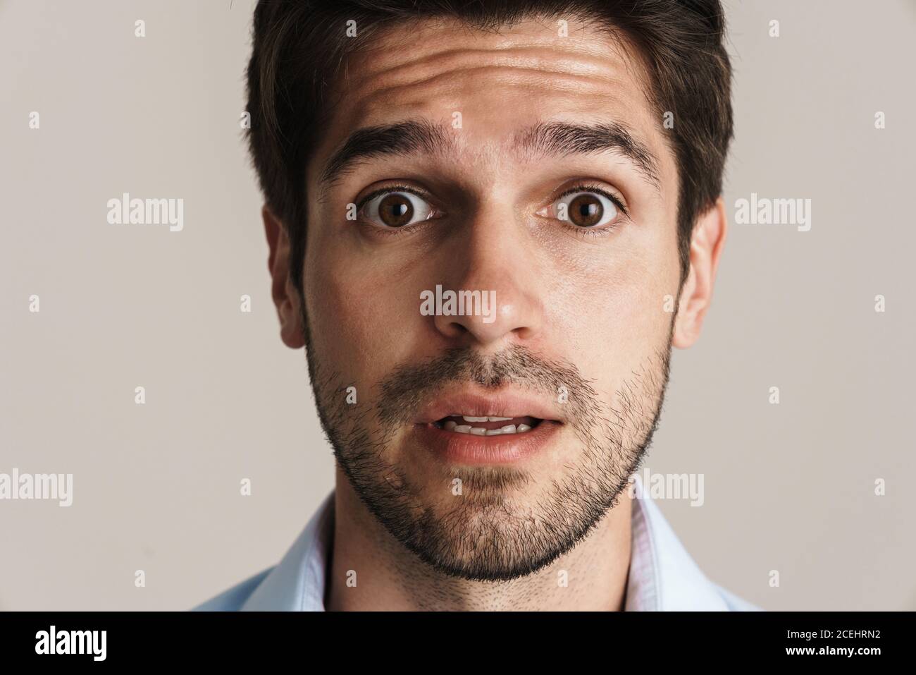 Image of young businesslike brunette man expressing surprise on camera ...