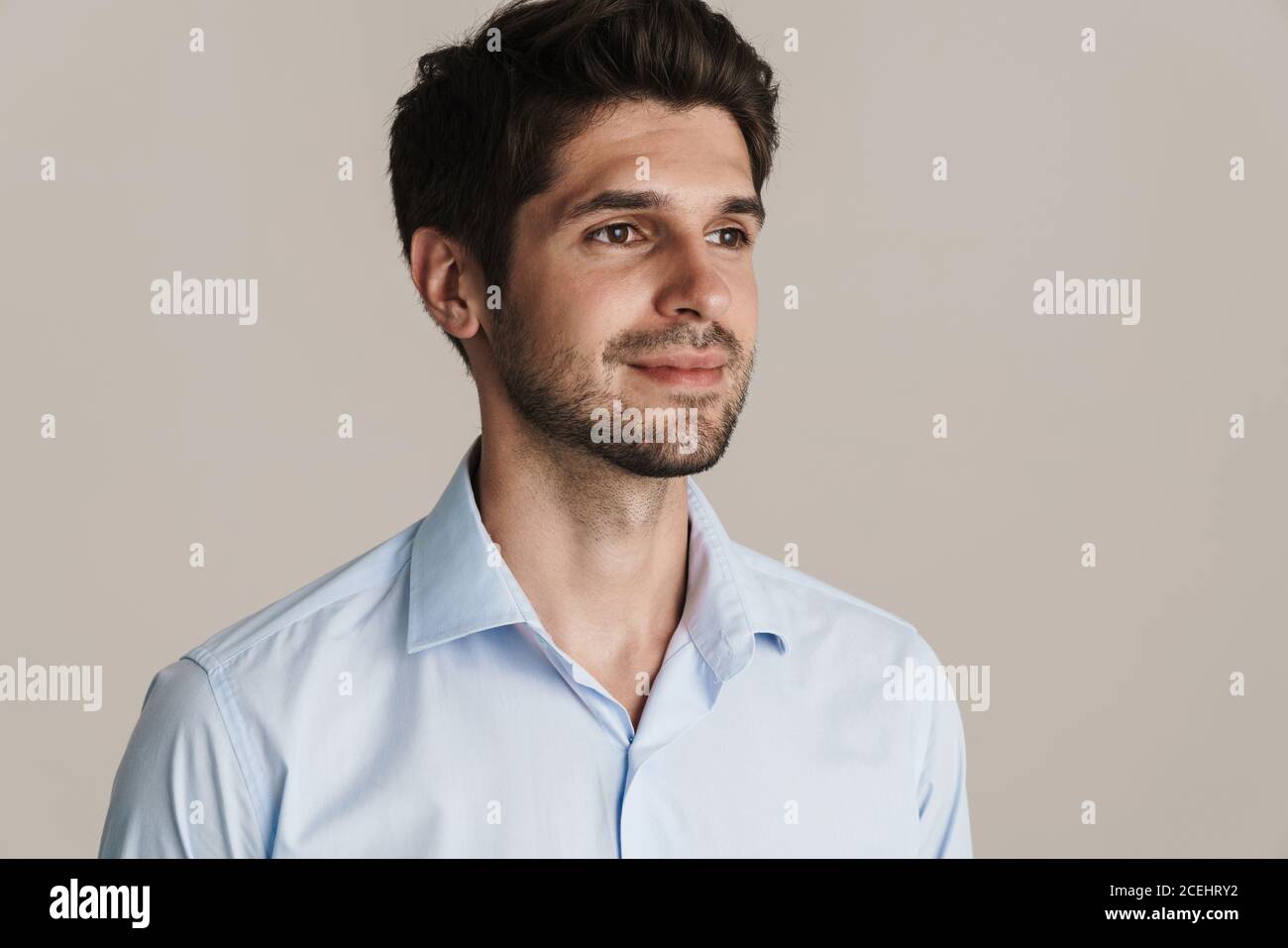 Image of pleased businesslike brunette man looking aside while standing ...