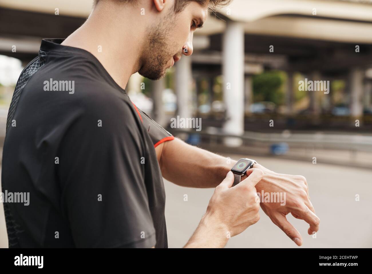 Image of athletic young sportsman using smartwatch while working out on ...