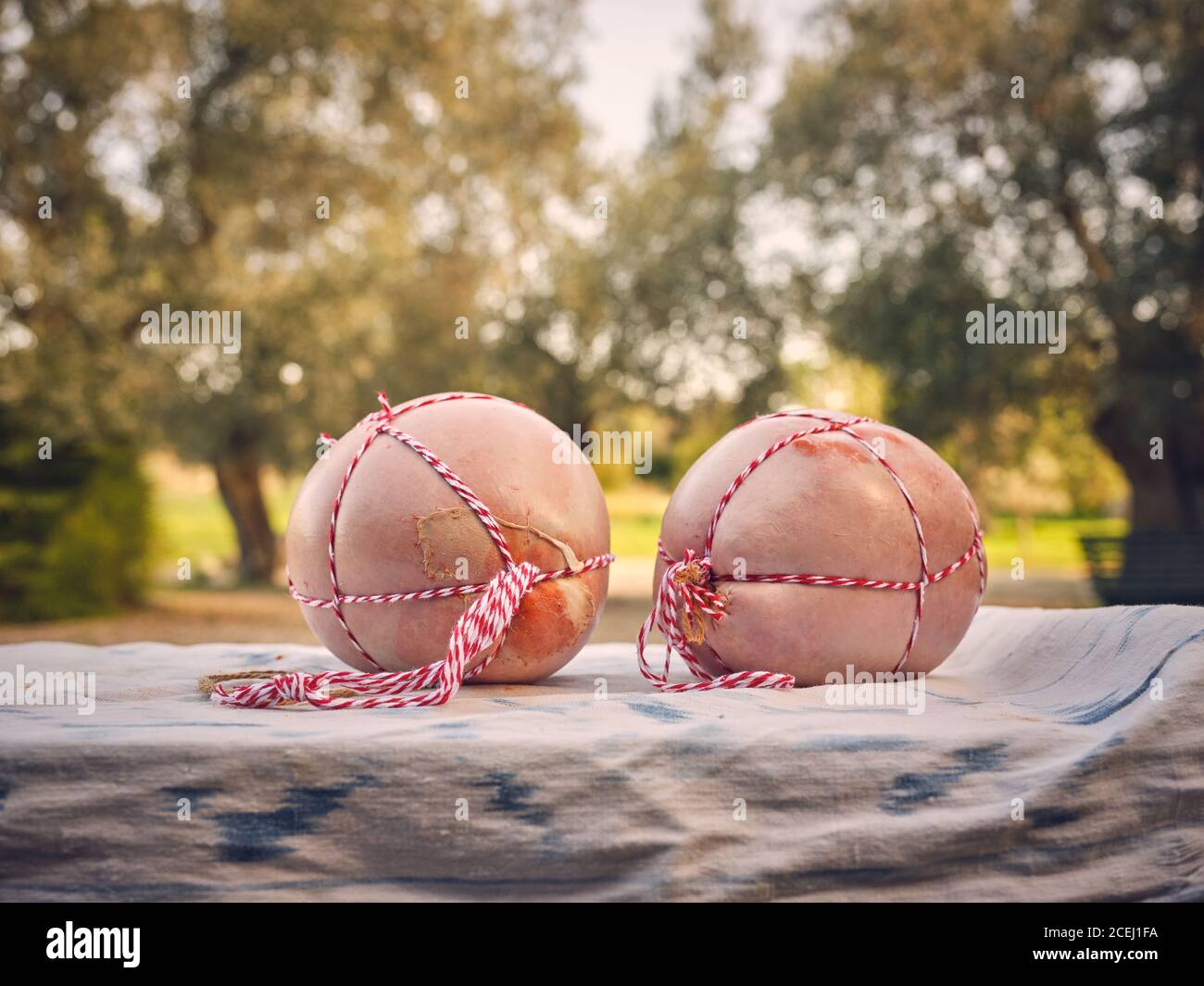Two natural sausage balls tied with striped rope lying on table on ...