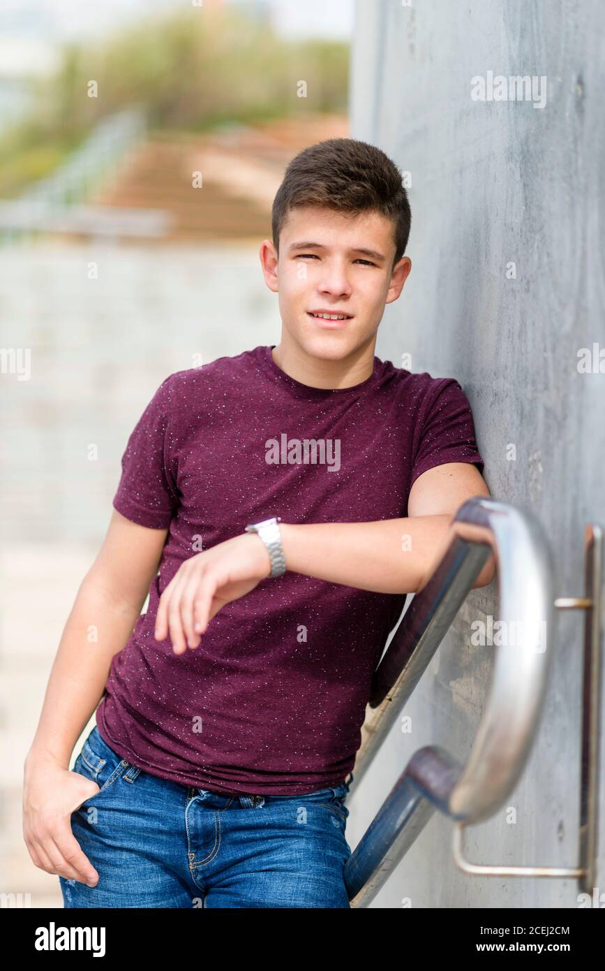 Front view of a trendy teenager leaning on a wall while looking camera ...
