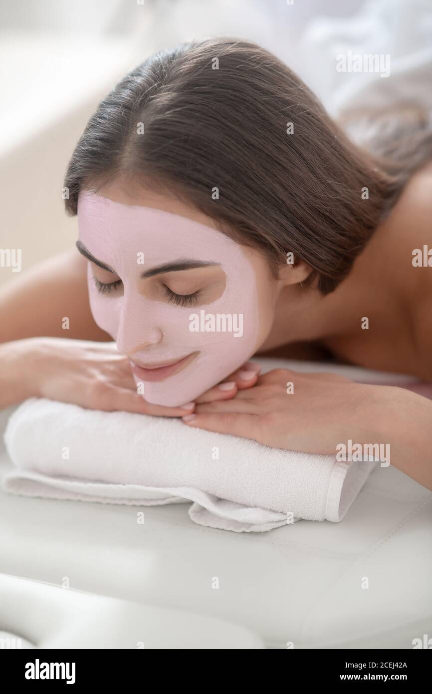 Young woman lying down with a mask on her face and smiling Stock Photo ...