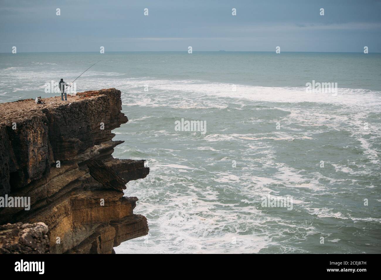 Fisherman fishing on a big cliff Stock Photo - Alamy