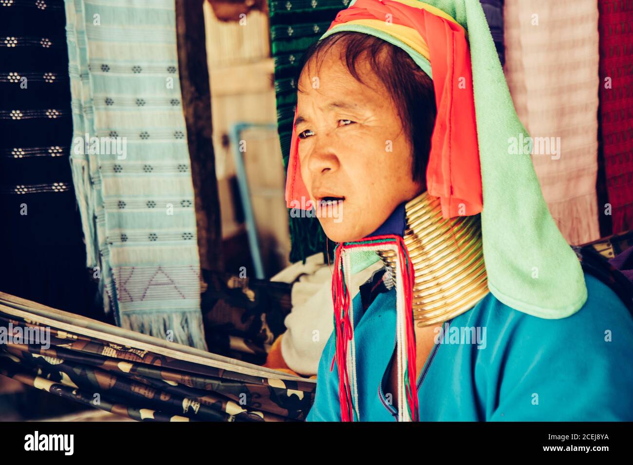 Portrait of Long Neck Woman weave cloth in front her house in tribal ...