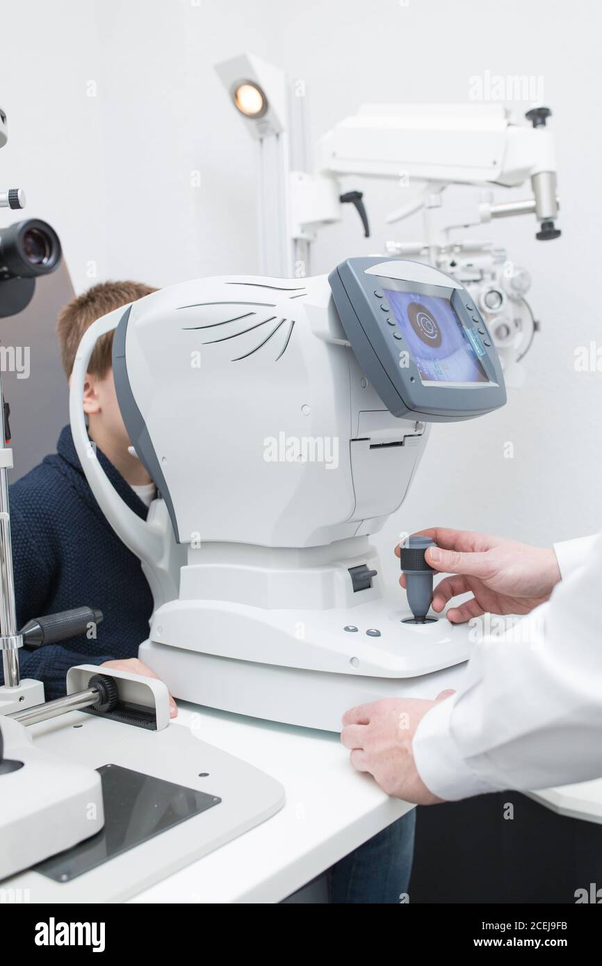 Optician testing a boy's eyes with optometry devices Stock Photo - Alamy