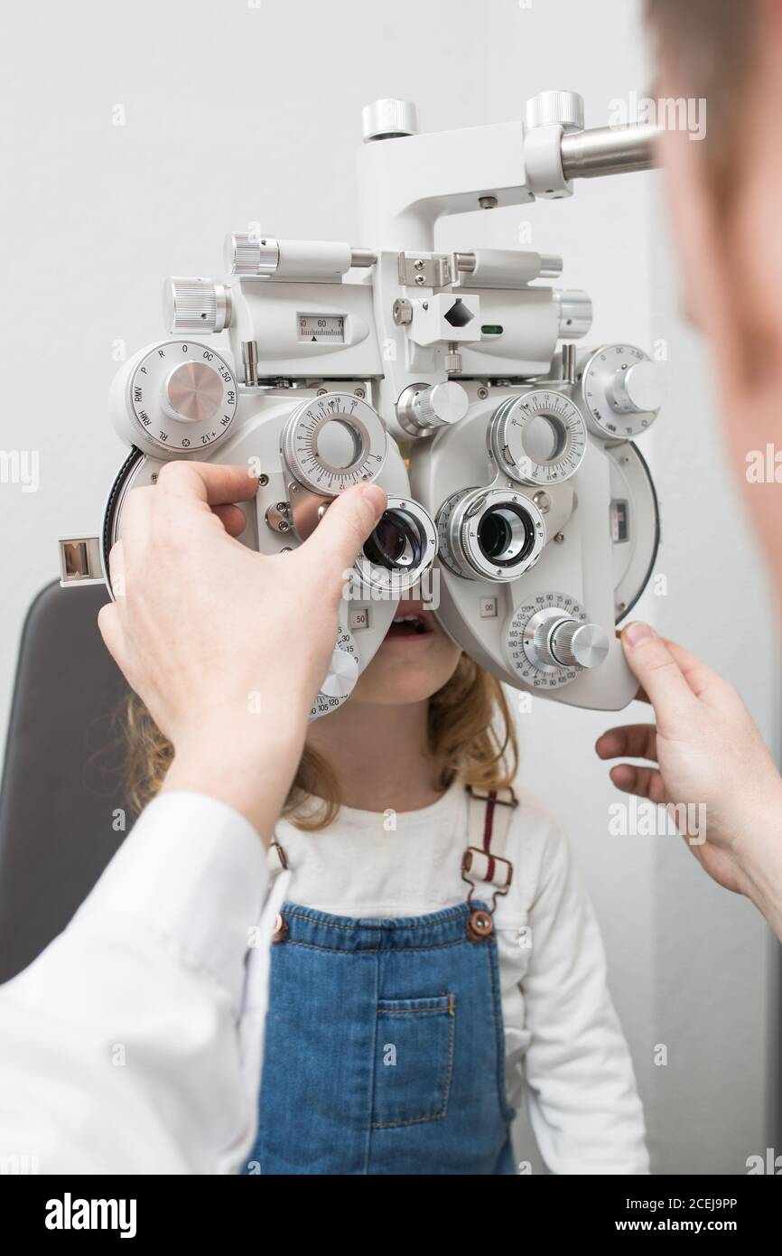 Optician testing a girl's eyes with optometry devices Stock Photo - Alamy