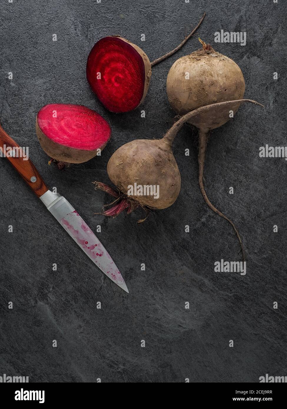 Beetroot cut in half and knife on dark table. Overhead shot with copy ...