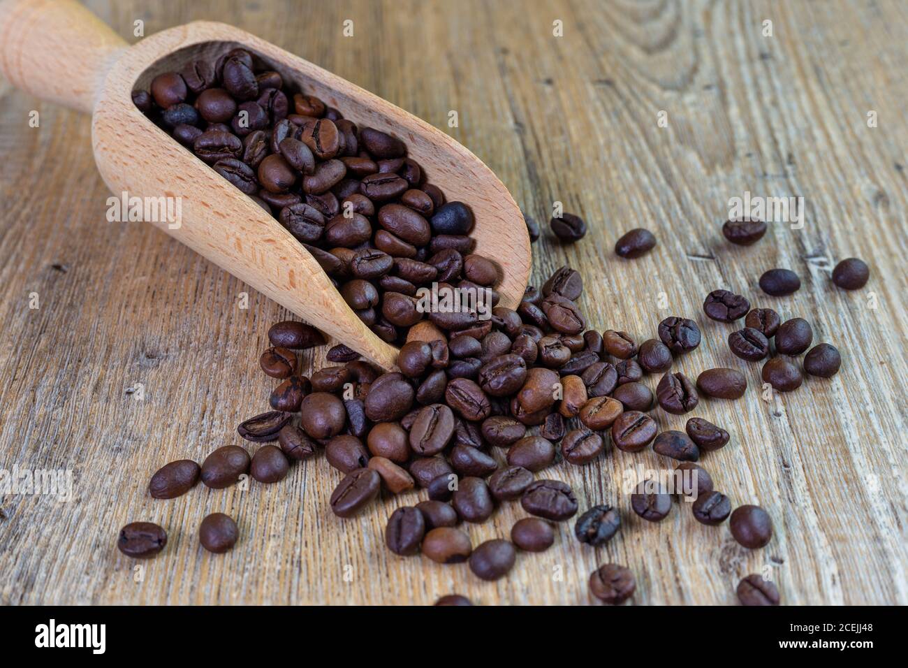 roasted coffee beans spilling from wooden spoon Stock Photo - Alamy