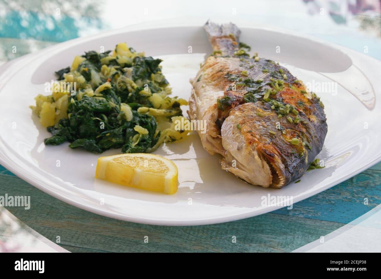 Balkan cuisine. Grilled fish ( sea bream ) with green leafy vegetables ...