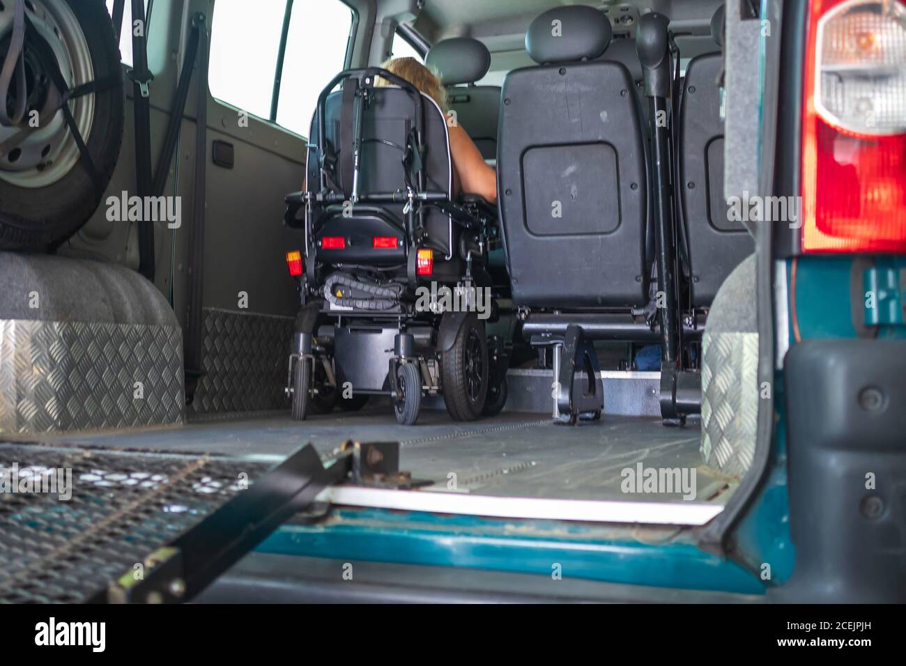Driver assisting disabled person on wheelchair with transport using ...