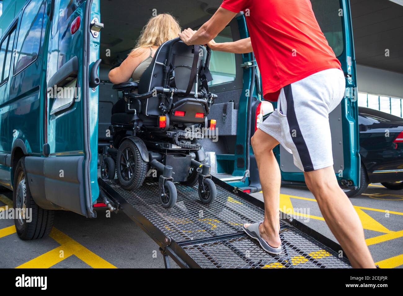 Driver assisting disabled person on wheelchair with transport using ...