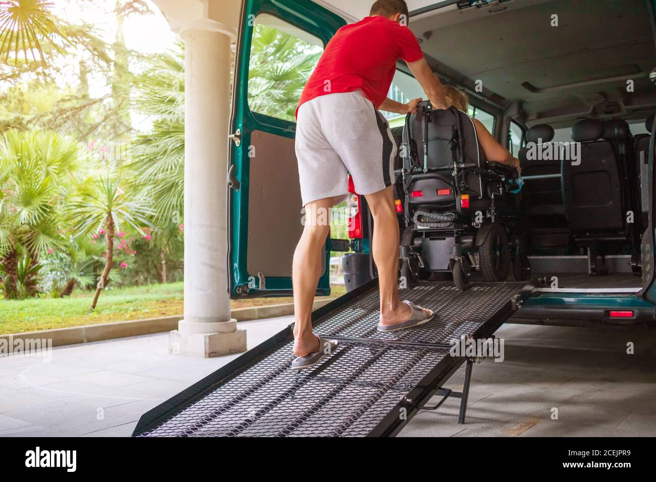 Driver assisting disabled person on wheelchair with transport using ...