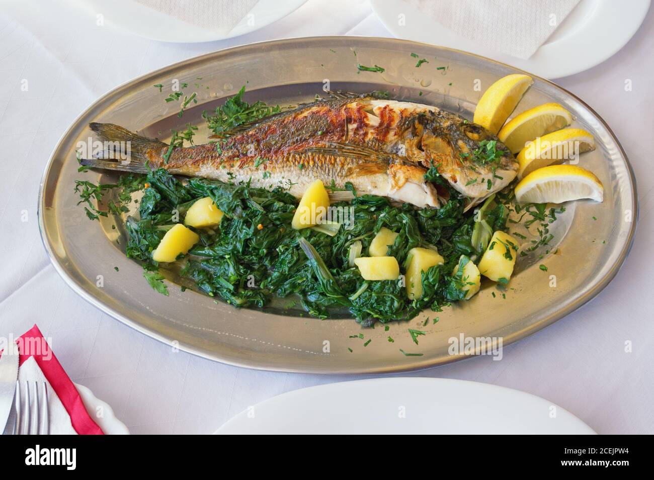 Balkan cuisine. Grilled fish (sea bream) with green leafy vegetables ...