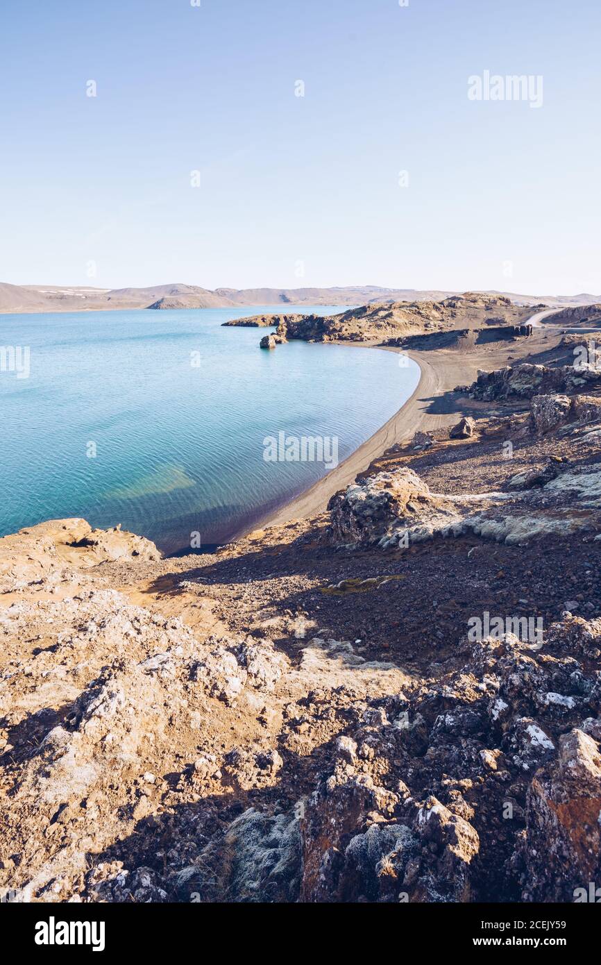Stone shore of wide river with blue water between hills in Iceland ...