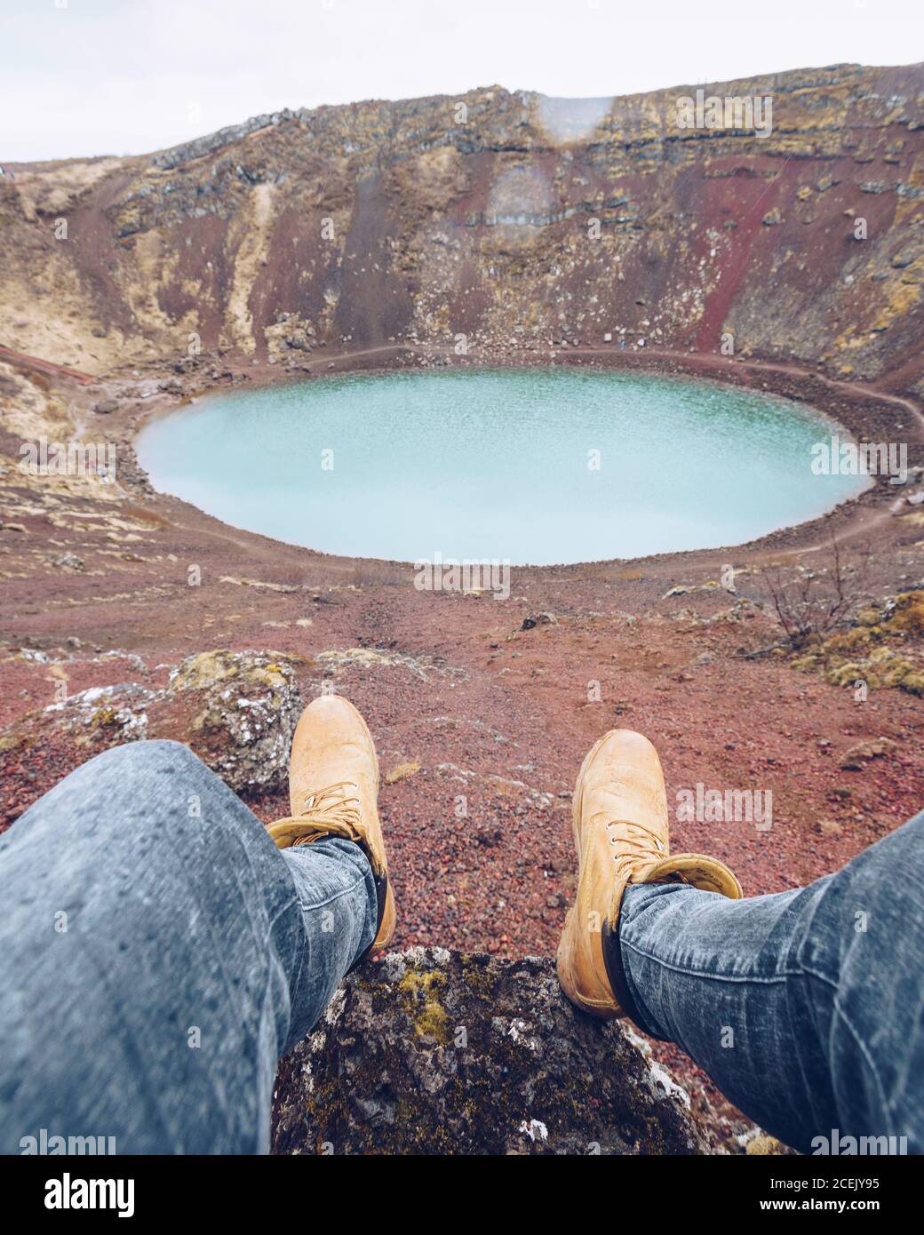 From above crop human legs near lake in crater between death brown ...