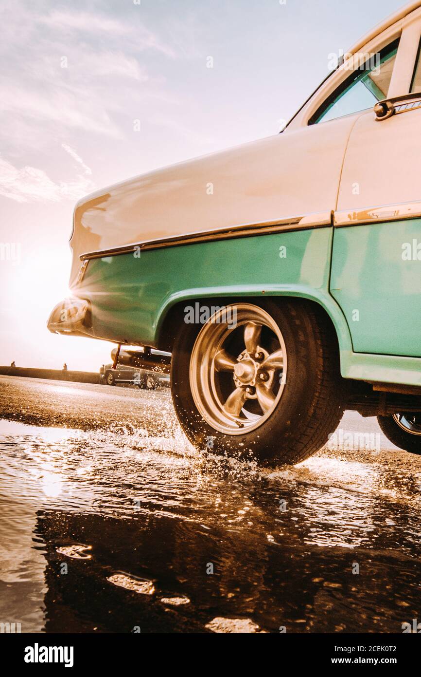 Amazing shiny vintage blue and pink car driving on road and splashing ...