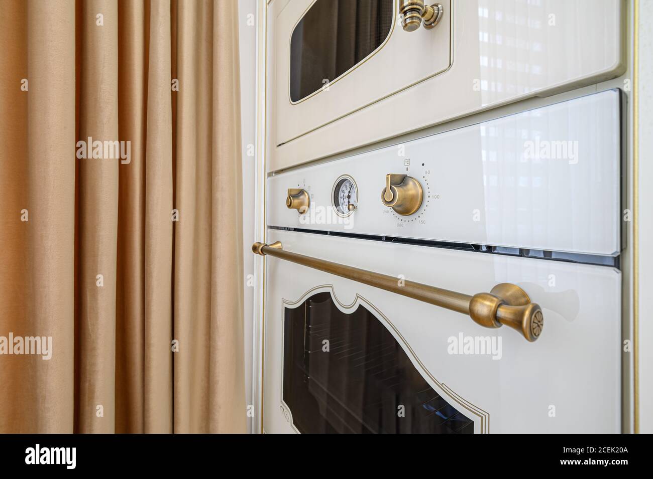 Electric and microwave ovens at beige kitchen interior Stock Photo - Alamy