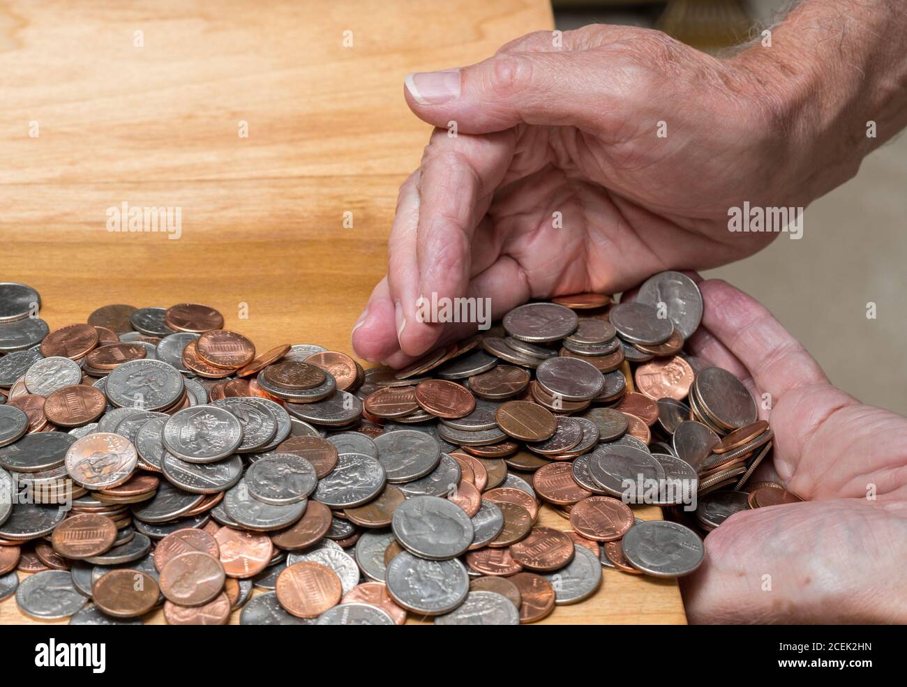 Hundreds of US coins being gathered into hands on wooden table as ...