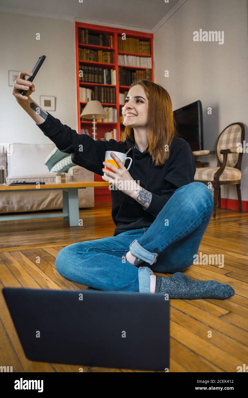 Woman taking selfie sitting on floor Stock Photo - Alamy