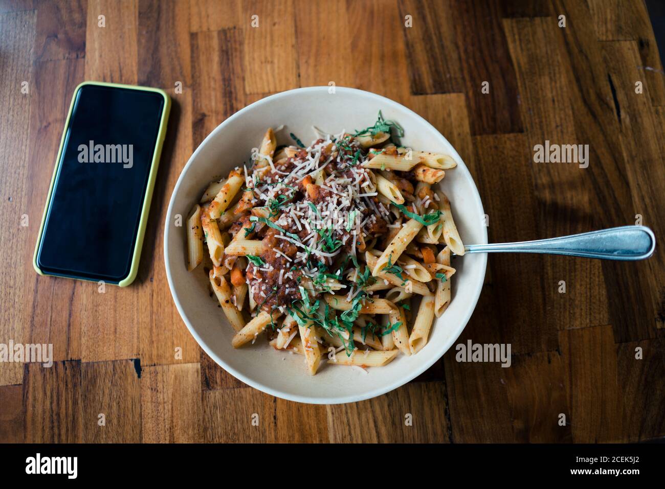 Smartphone near macaroni bolognese with meat sauce with tomato and ...