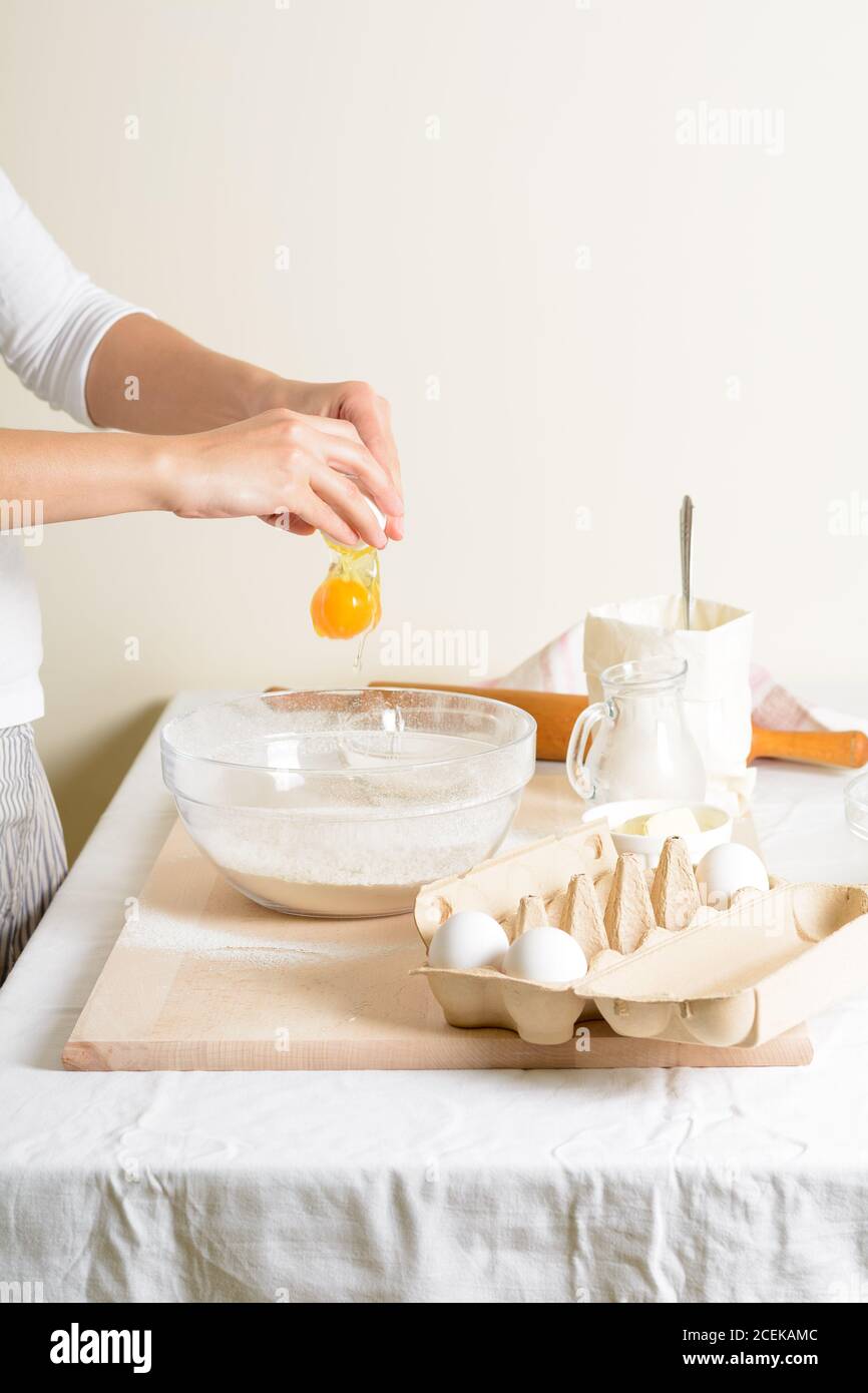 Crop Woman pouring egg in bowl Stock Photo - Alamy