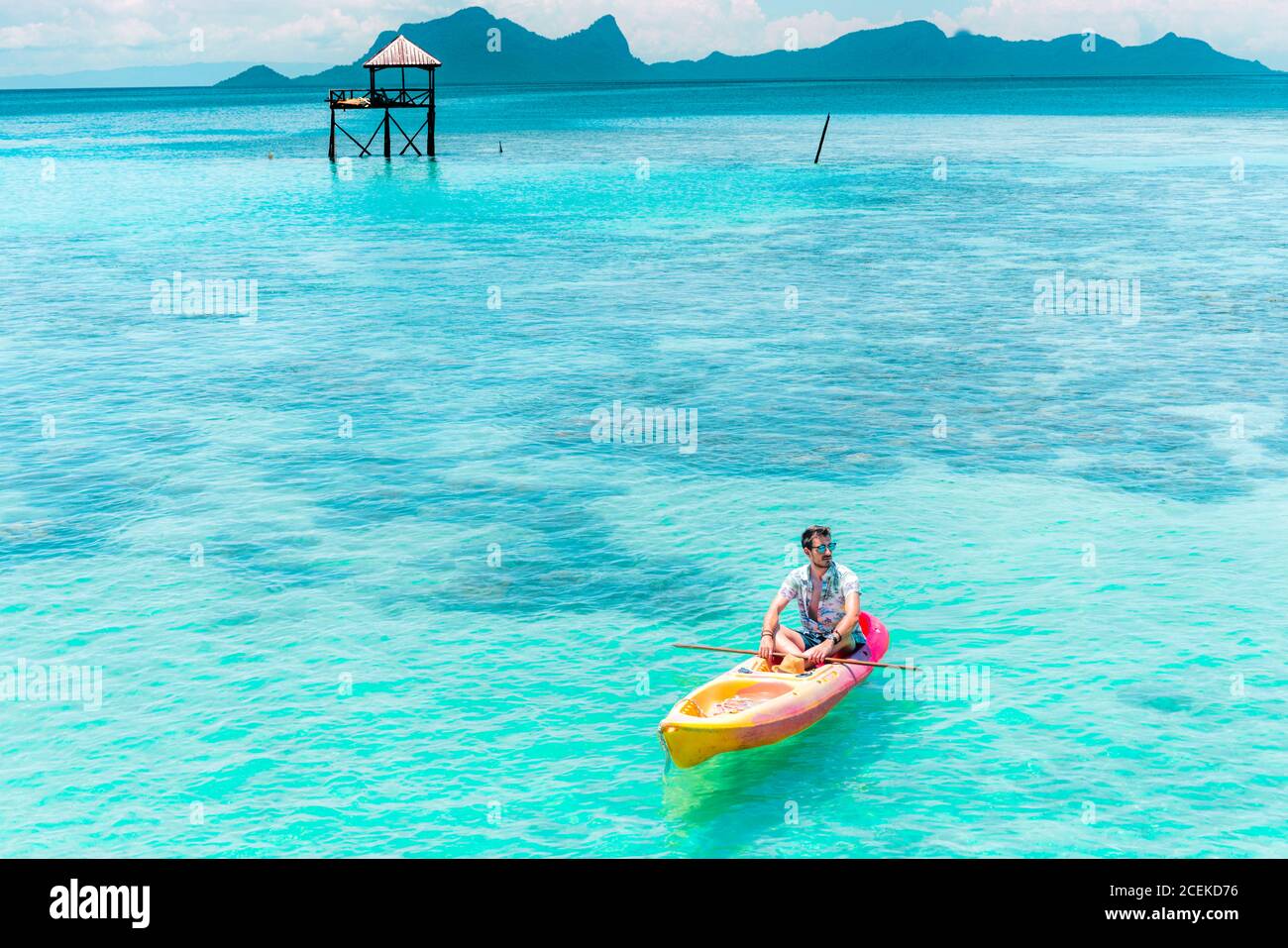 male boating on canoe with paddle on amazing azure sea and blue sky in ...