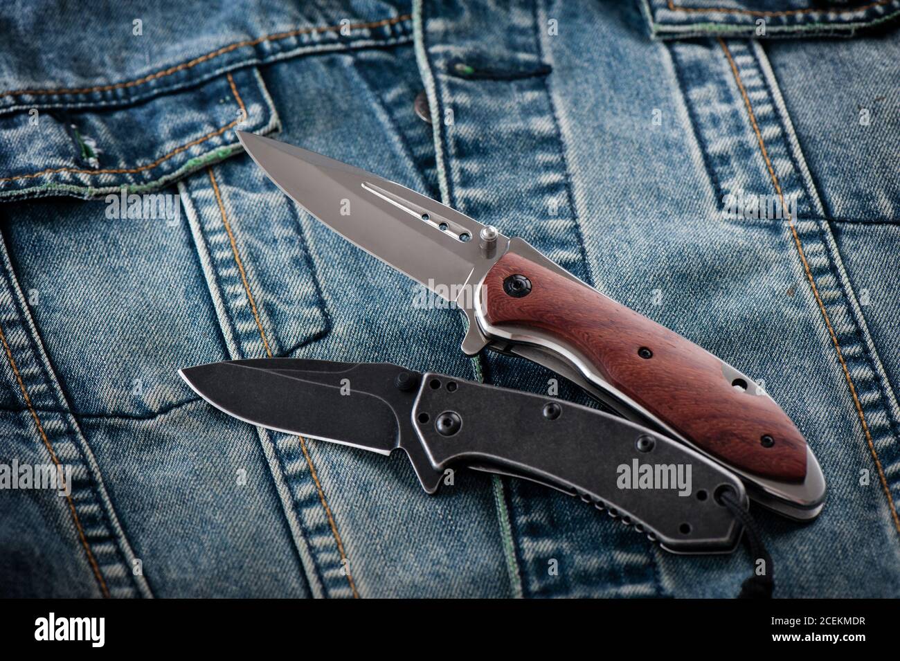 two stainless steel folding knifes over denim jacket Stock Photo - Alamy