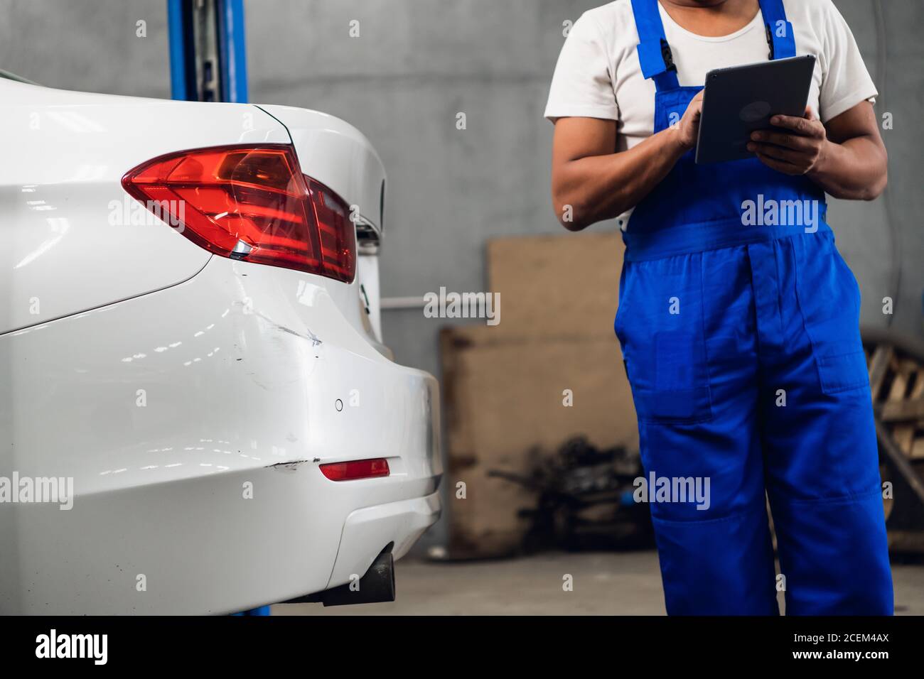 A workshop worker with a clipboard looks for damage on a car Stock ...