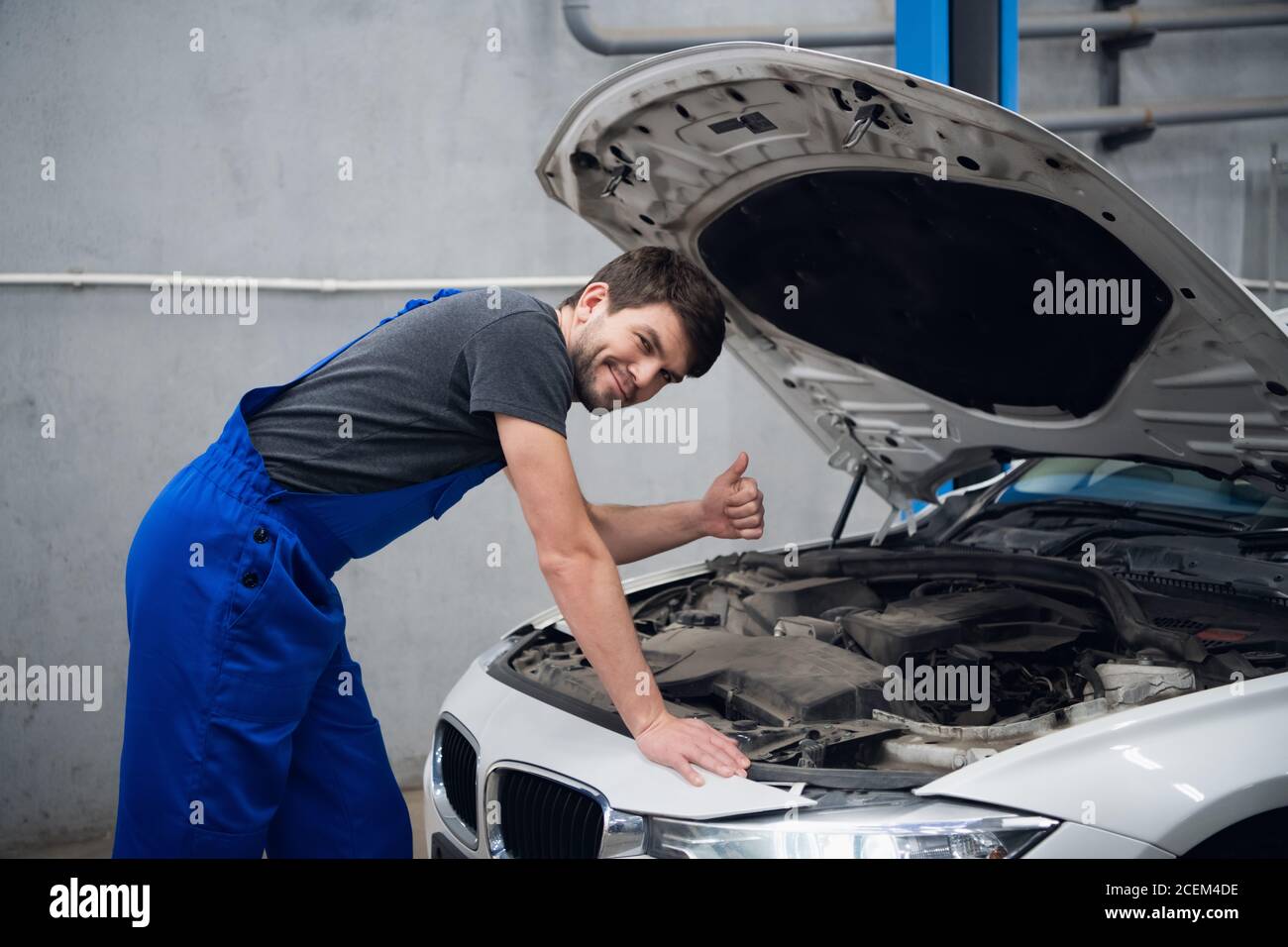 A mechanic inspects a car engine and shows a thumb. He smiling Stock ...