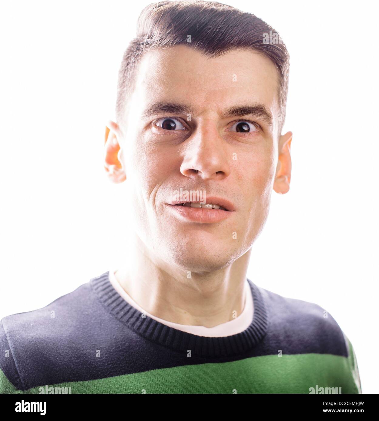 Portrait of a smart serious young man standing against white background ...