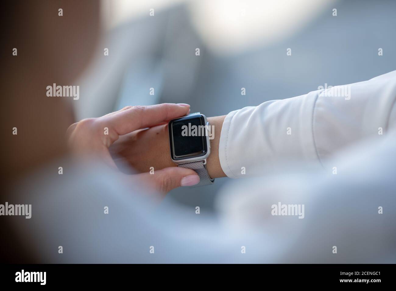 Woman in white shirt looking at the smartwatch Stock Photo - Alamy
