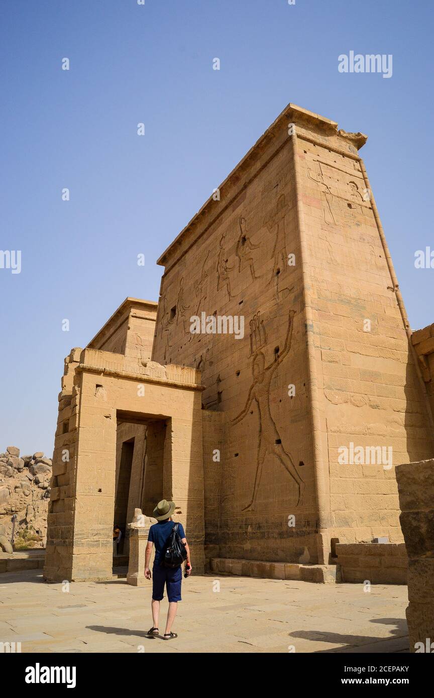 Low angle shot of a male standing in front of Isis Aswan Temple in ...