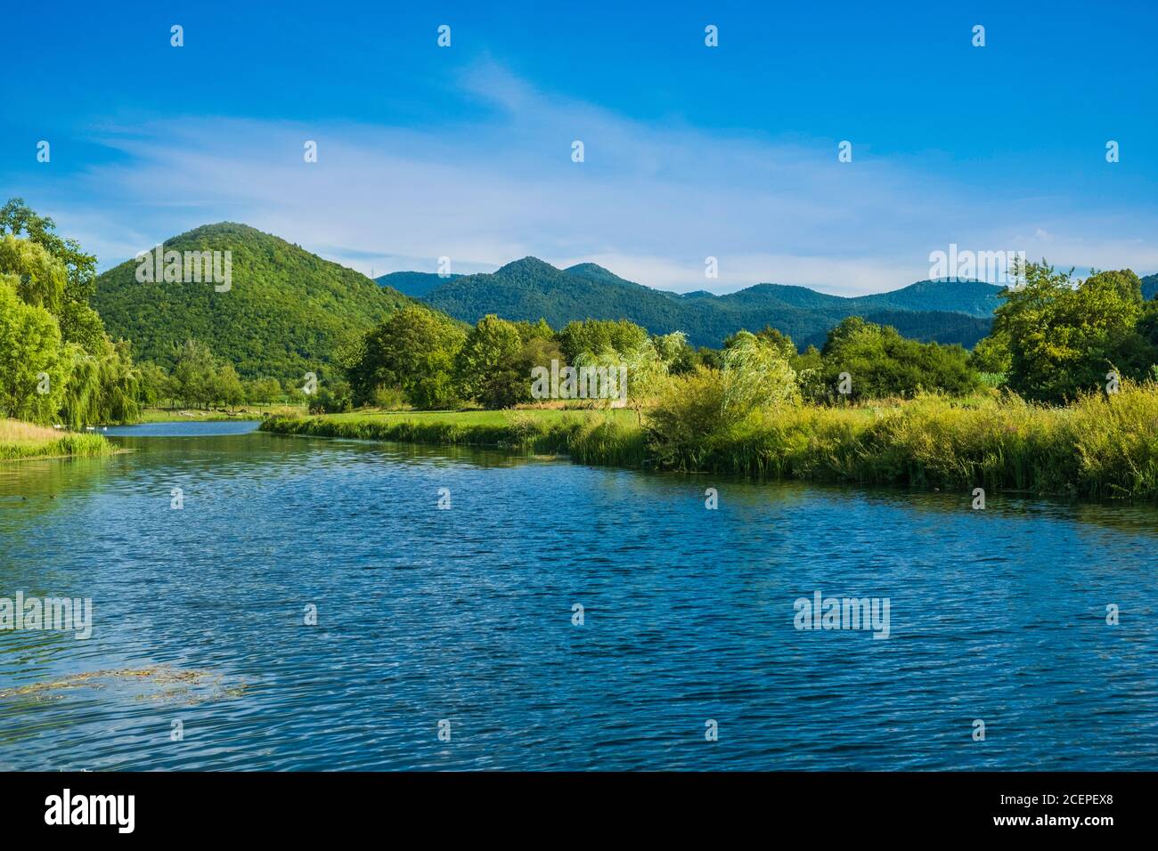 Gacka river flowing between green fields in Lika region of Croatia ...