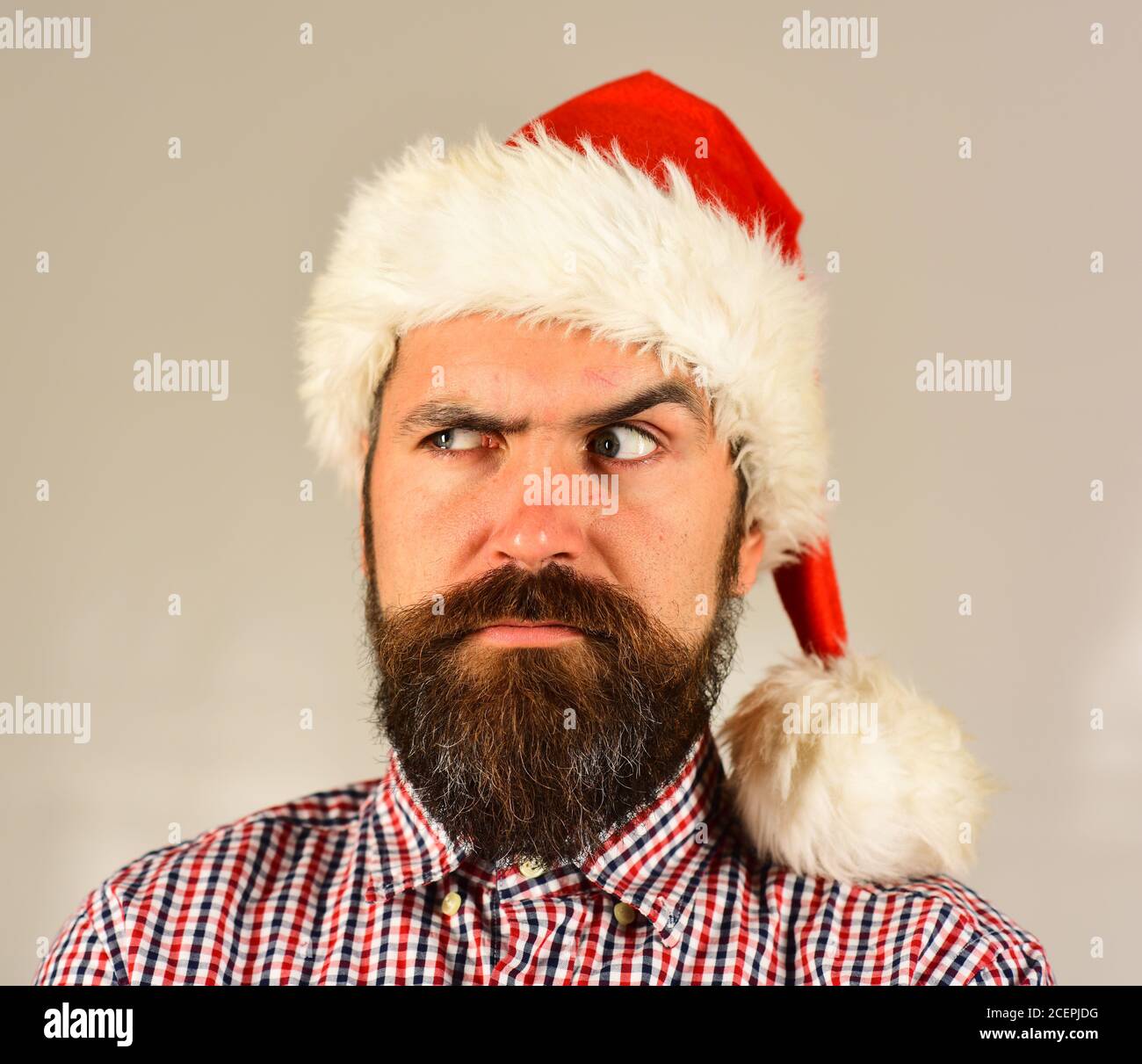 Man with suspicious face on grey background. Guy in plaid shirt and ...