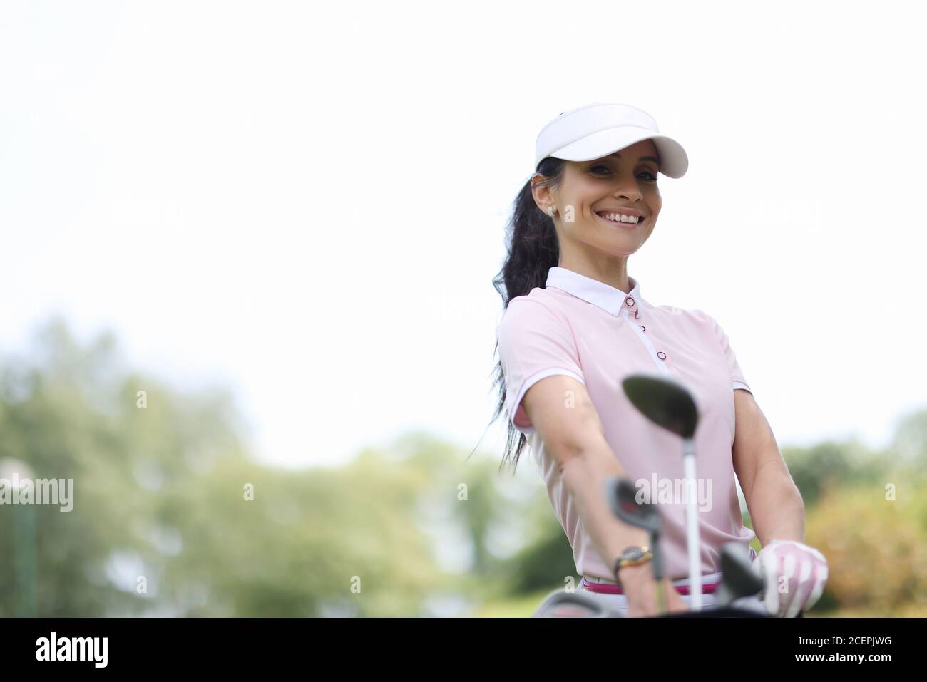 Female golfer smiles and holds bag of golf clubs Stock Photo - Alamy